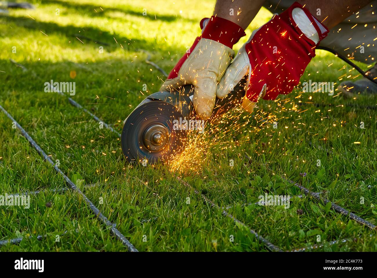 Cutting metal net with grinder on green grass. Sparks from contact ...