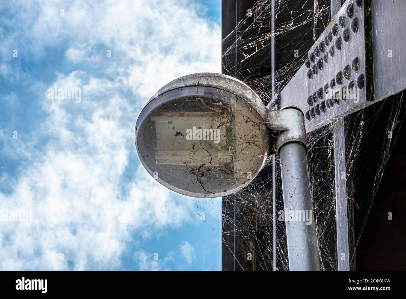 Spider web on a public street lamp attached to a steel railway bridge ...