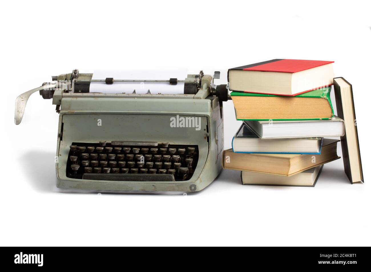 an old grungy manual typewriter with a stack of old books isolated on ...