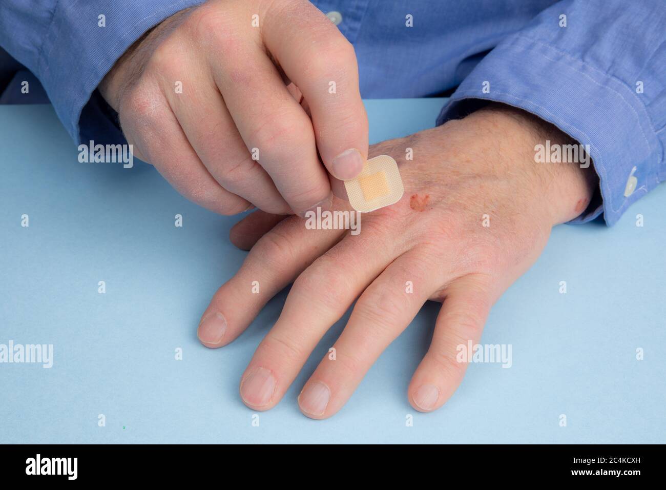 closeup as an elderly male places a small square bandage on a wound on ...
