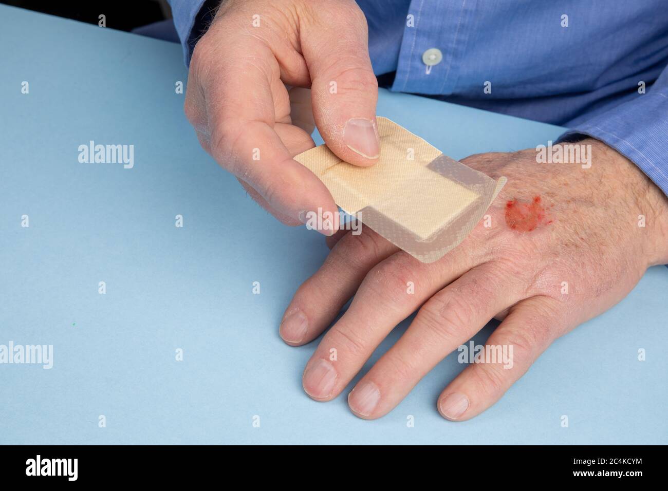 closeup as an elderly male places a large square bandage on a wound on ...