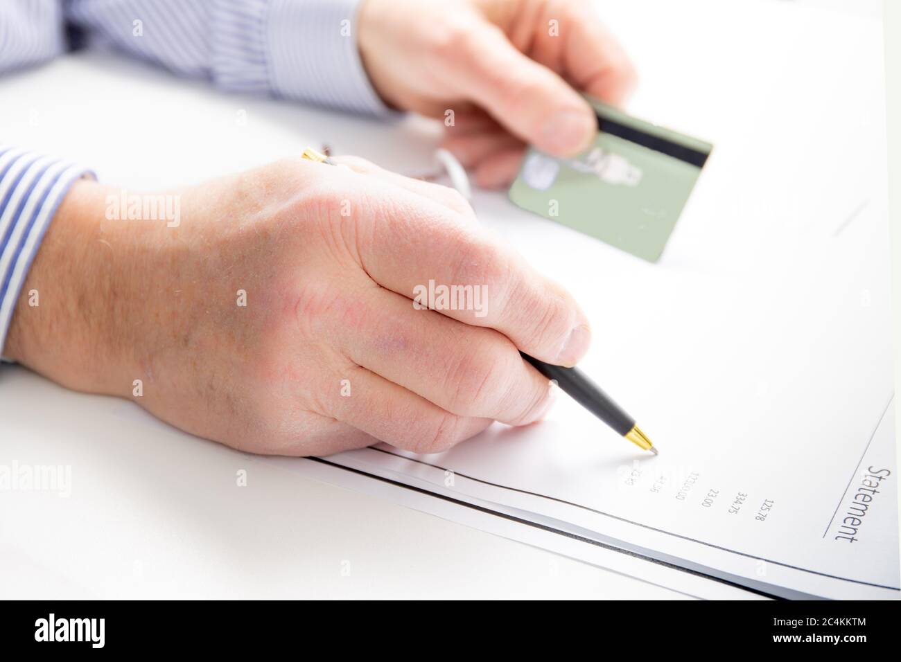 a man with several credit cards checks his statement with a pen on a ...