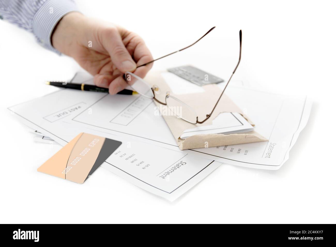 a man's hand holds his glasses over a stack of past due credit card ...