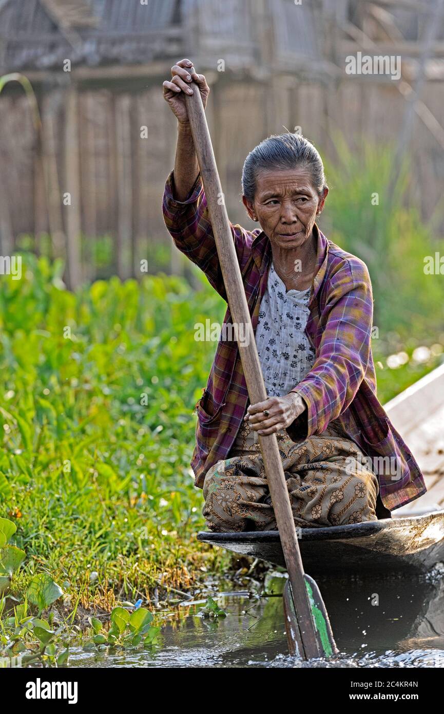 A Myanmar woman paddling her canoe through the village of Pwe Sar Kone ...