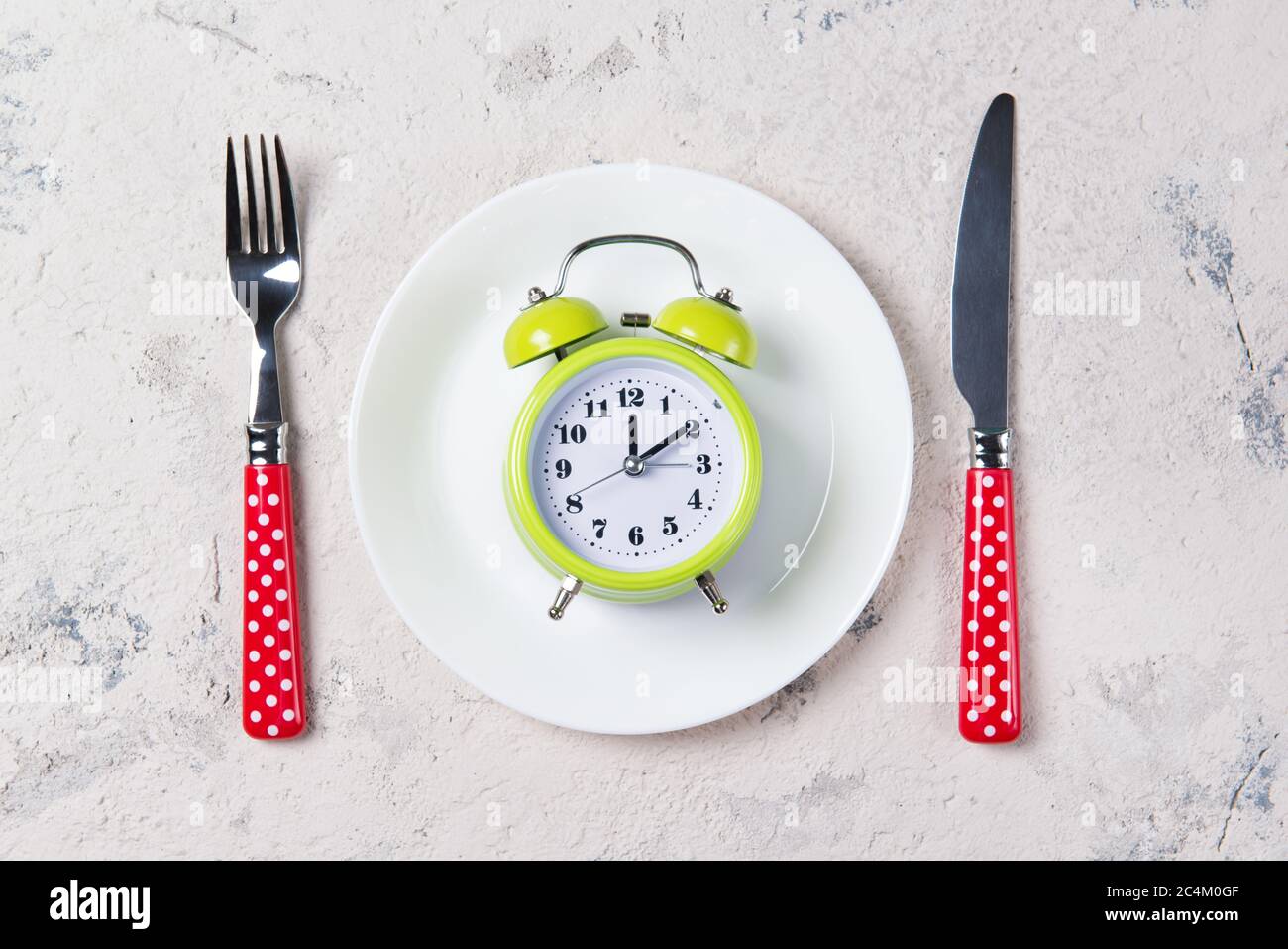 Green retro alarm clock with bells on the plate with fork and knife ...