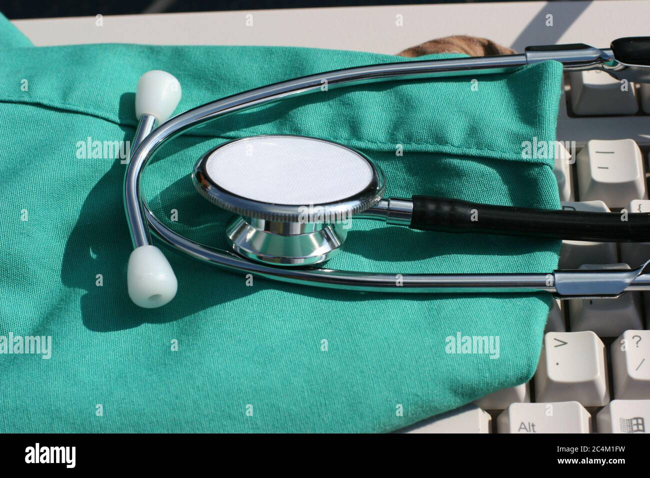 Medical stethoscope. laying on nurse's green scrubs & computer keyboard ...