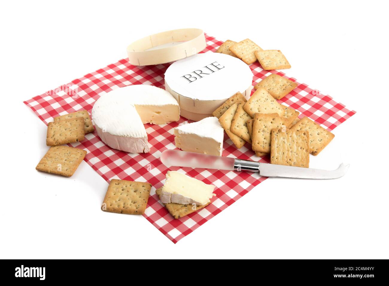 a round of brie cheese with a piece cut out with multigrain crackers on ...