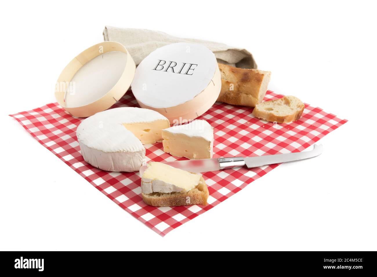 round of brie cheese with a French baguette on a red checked table ...