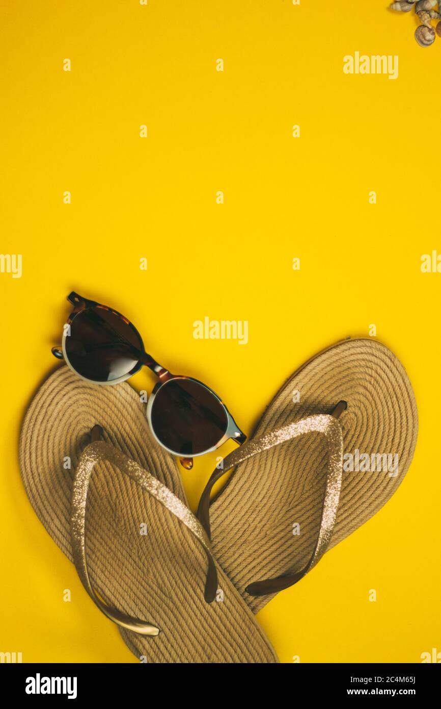 Closeup shot of the straw flip flops with sunglasses on yellow ...