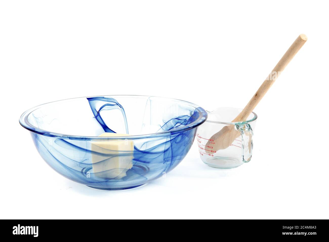 a blue glass mixing bowl with butter and an empty measuring cup ...