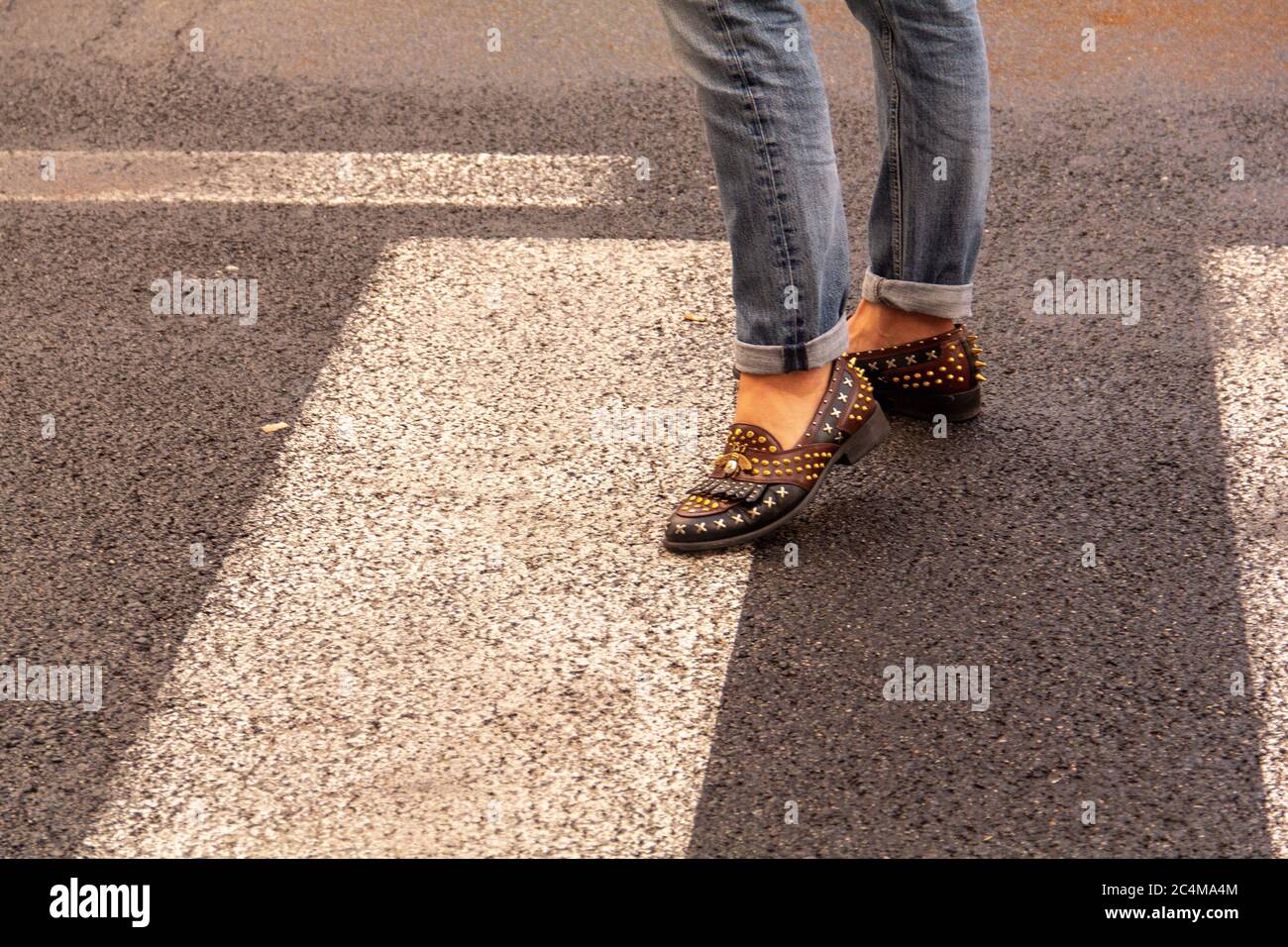 Person crossing an asphalt street wearing modified shoes with pins on ...
