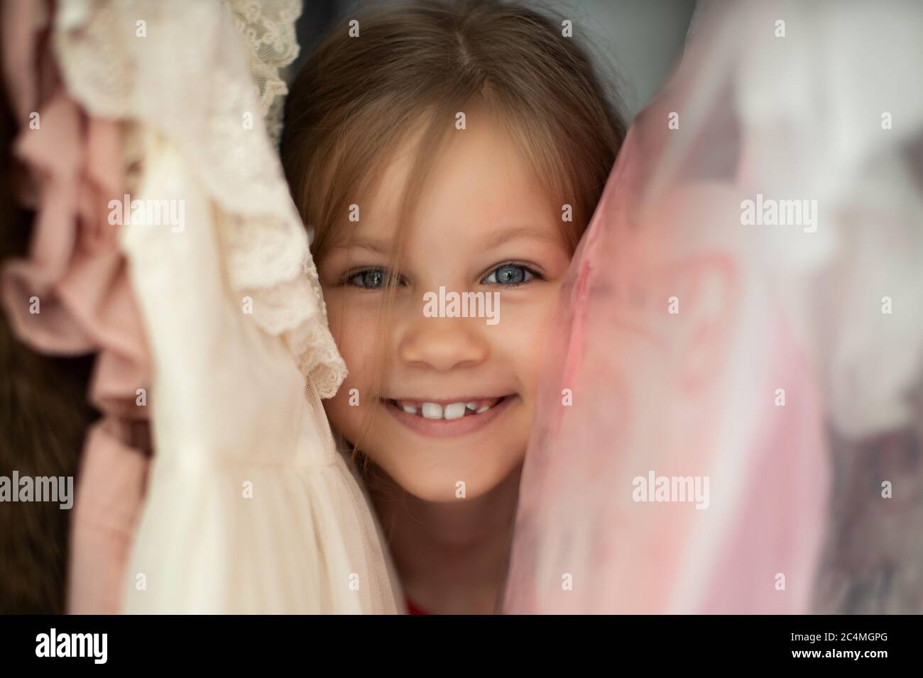 Close-up view of girl standing between clothes Stock Photo - Alamy