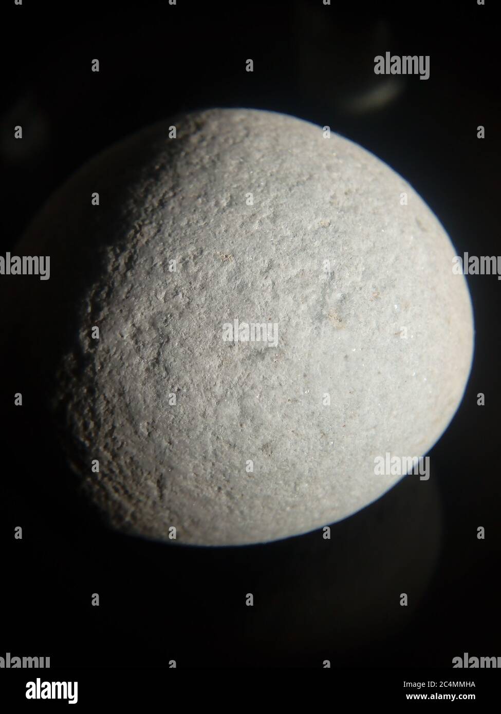 Round gray stone isolated on a black background Stock Photo - Alamy