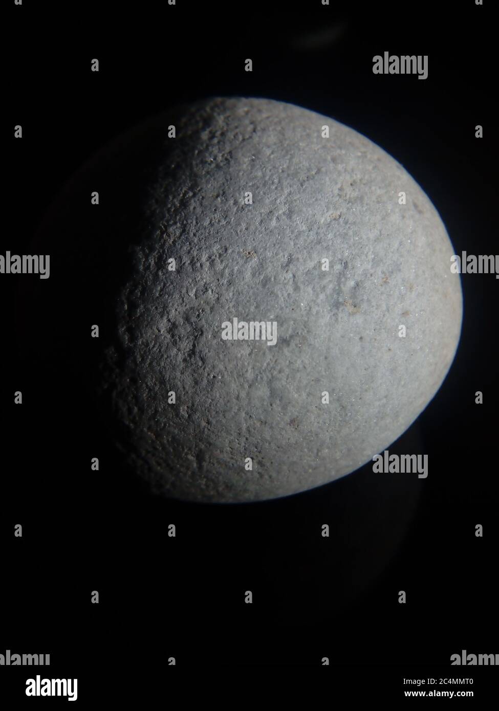 Round gray stone isolated on a black background Stock Photo - Alamy