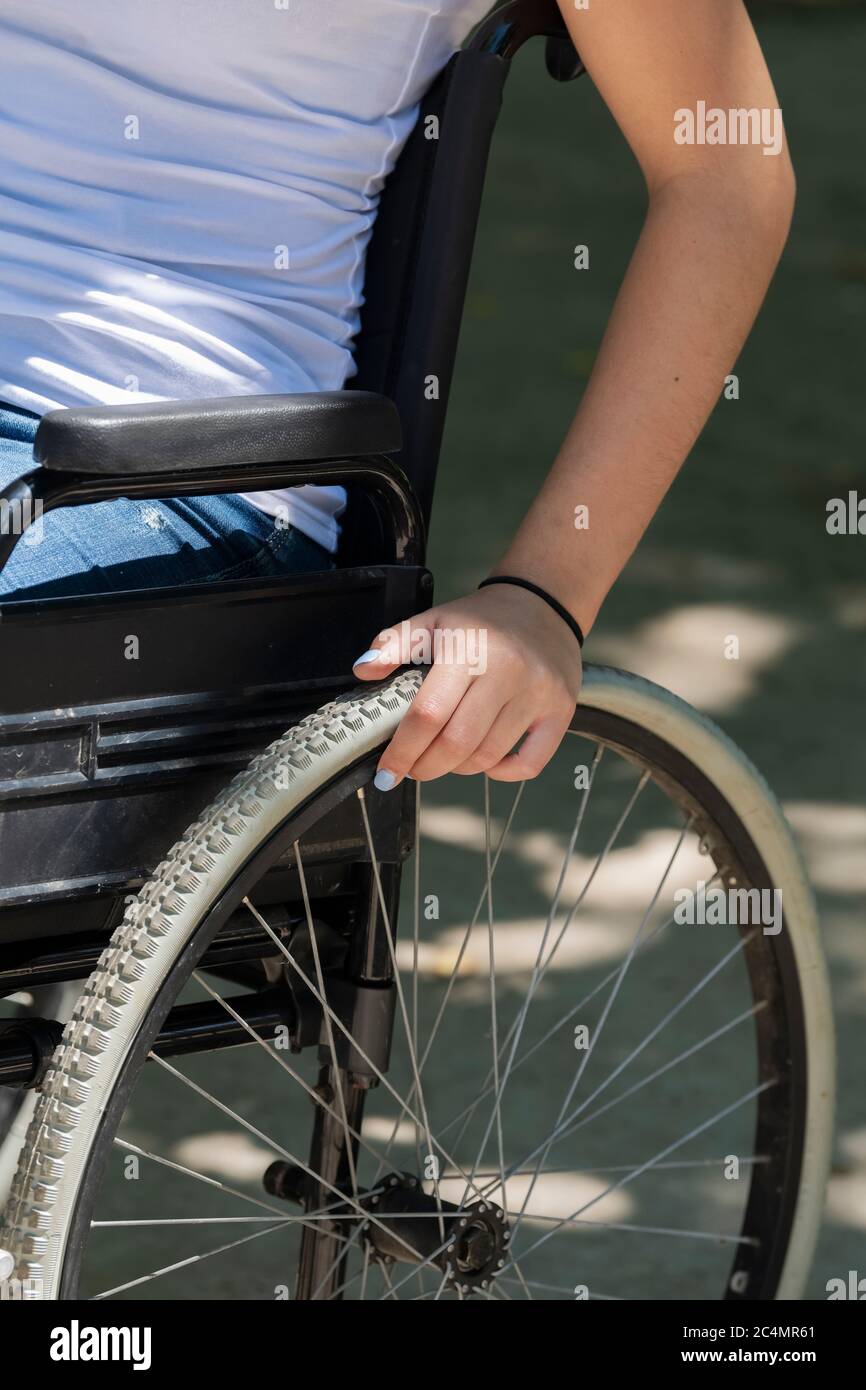 Close up of a female arm handling the wheel of a wheelchair on an out ...