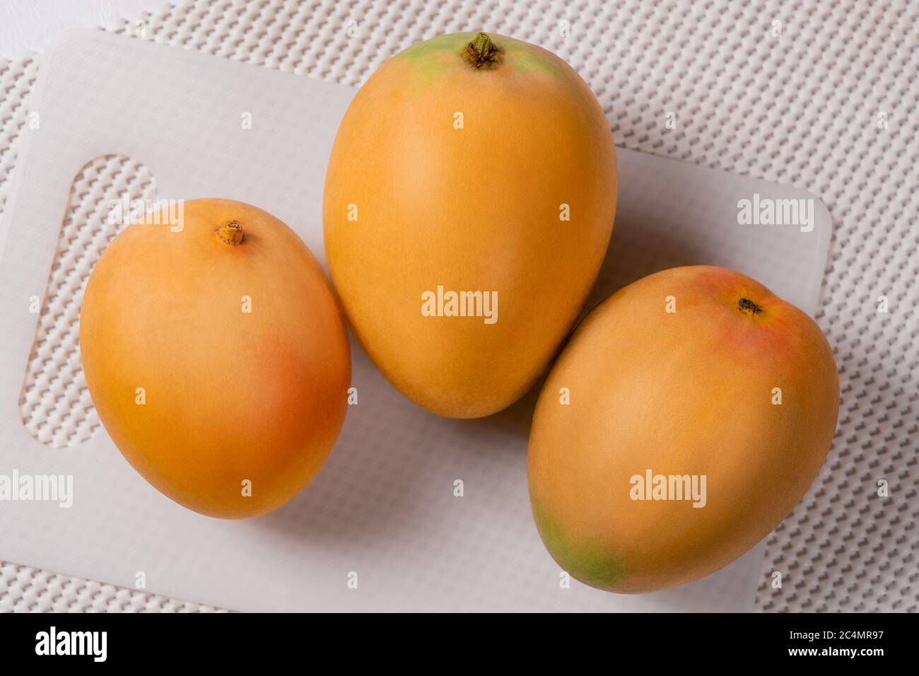 Top view of three mangoes on a white kitchen table Stock Photo - Alamy
