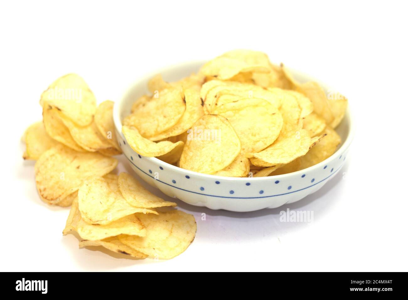 A bowl of potato chips with some spilled chips on the side isolated on ...