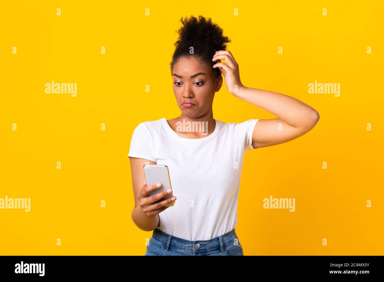 Confused young african woman using mobile phone Stock Photo - Alamy