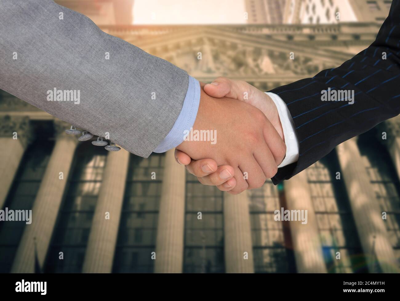 Funds manager shaking hands with investor in front of stock exchange ...