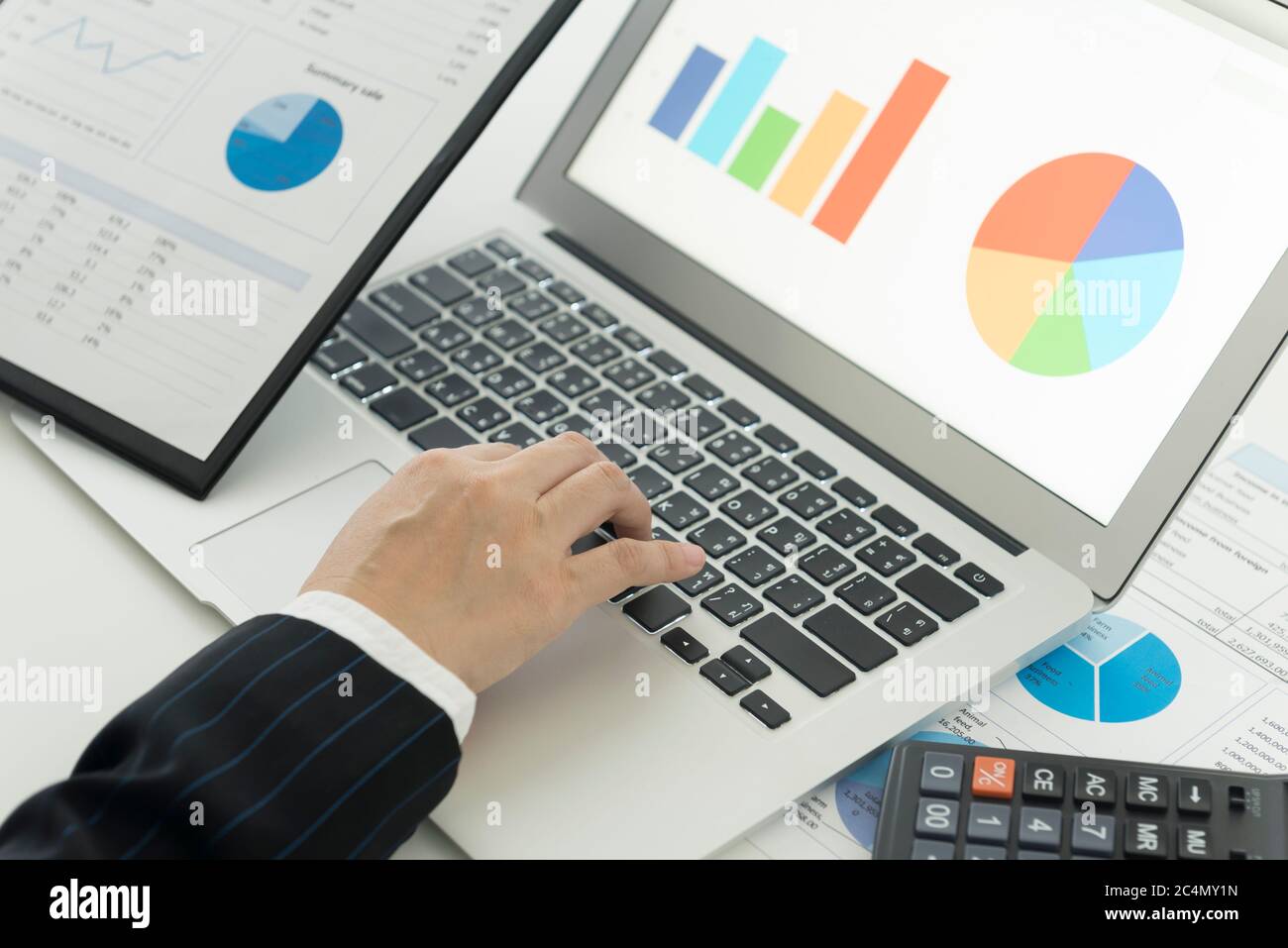 Businessman analyzing investment charts and business graphs with laptop ...