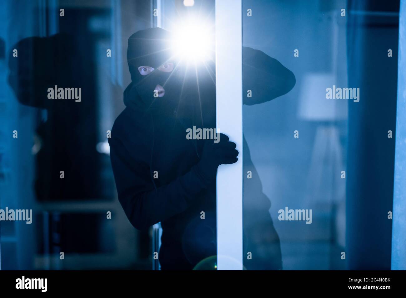 Scared thief breaking into apartment to steal, using torch Stock Photo ...