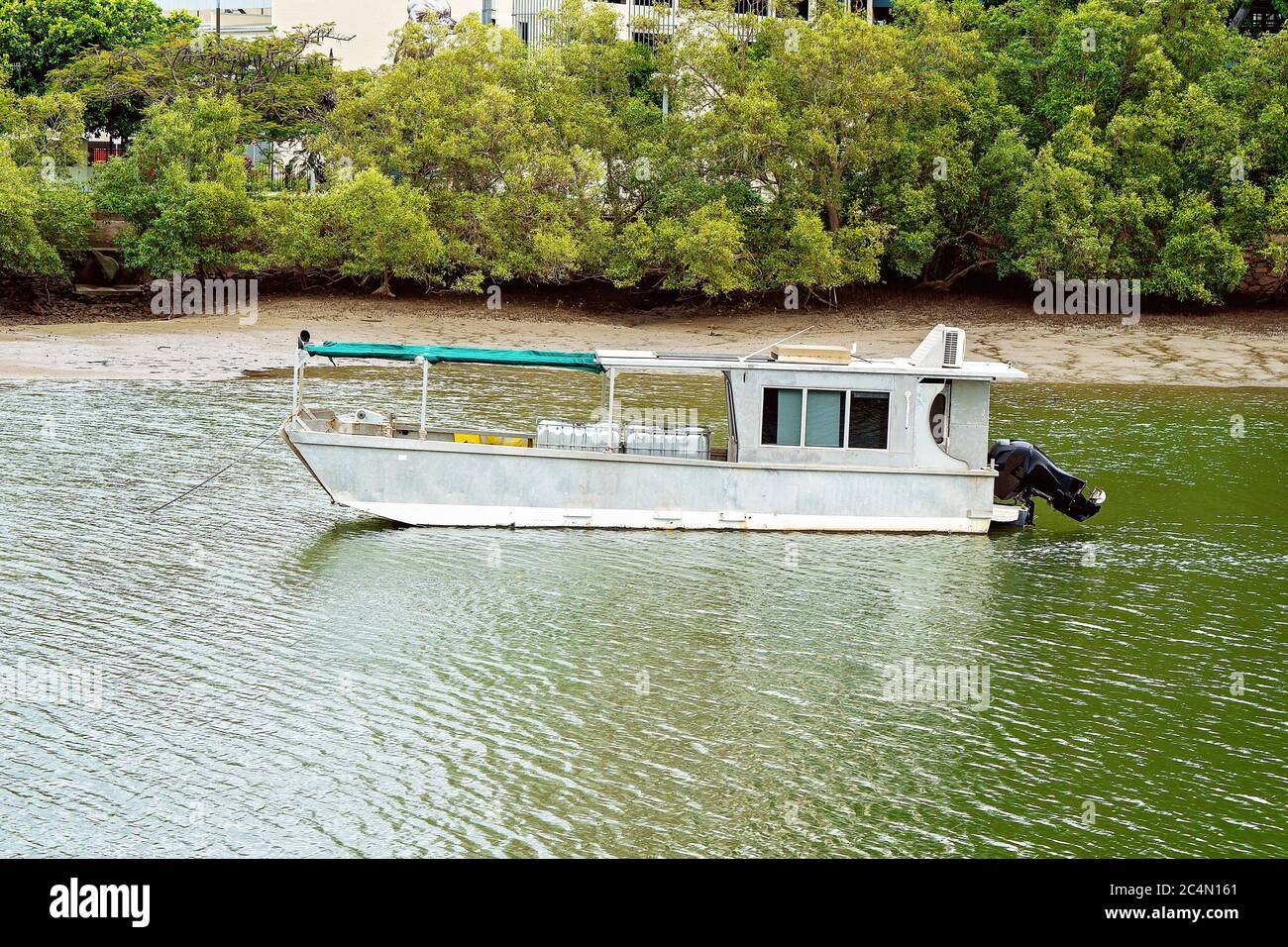 A vintage aluminium tin boat barge with modern outboard motor anchored ...