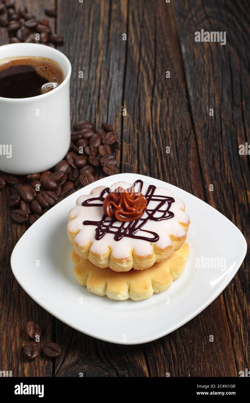 Small round cake with chocolate cream and cup of coffee on dark wooden ...