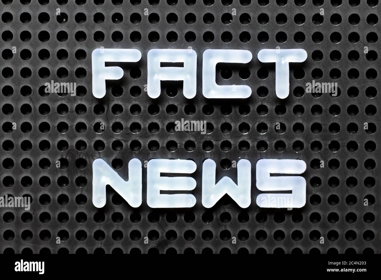 White color alphabet with word fact news on black pegboard background ...