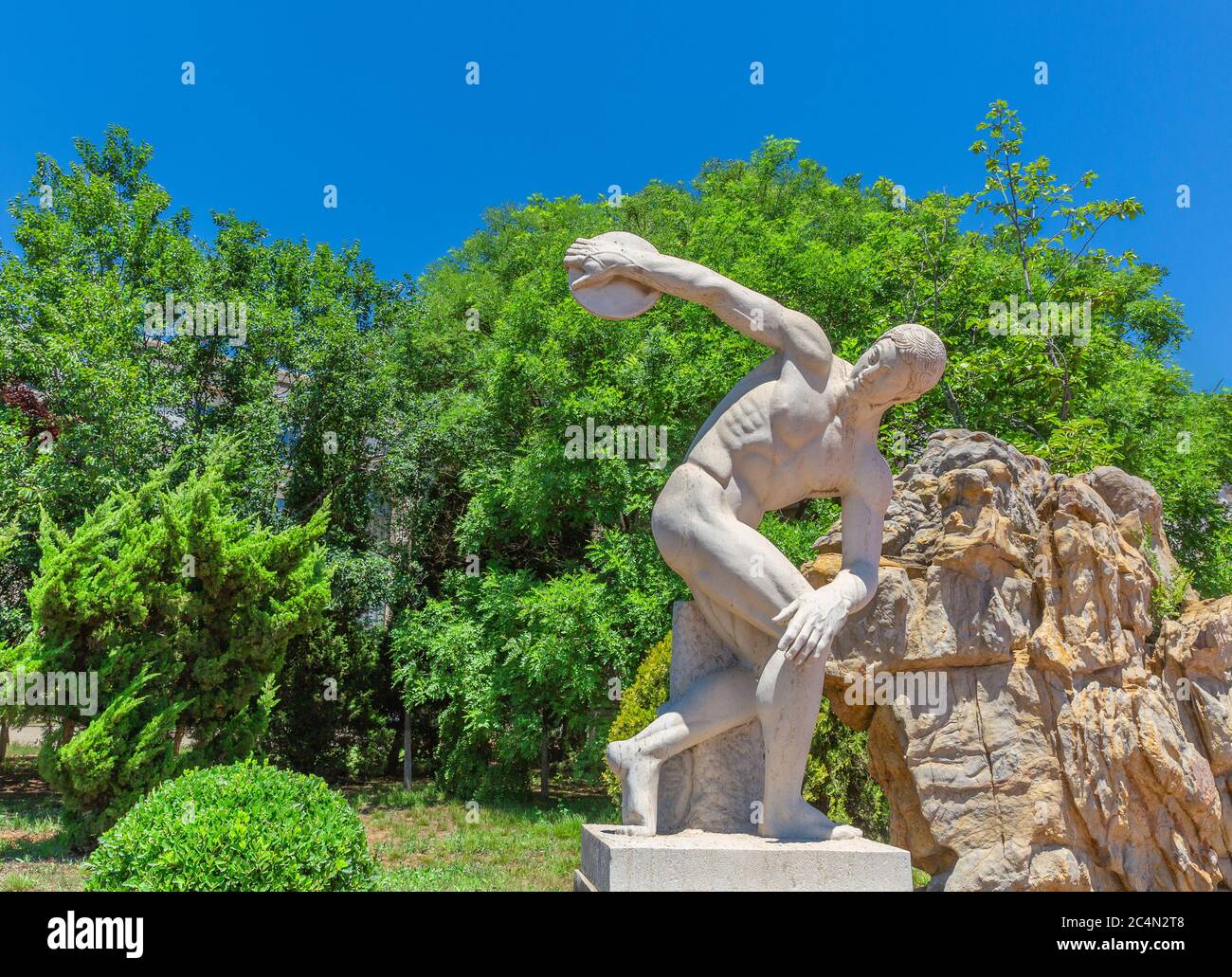 Outdoor blue sky, green tree and discus thrower sculpture, Greek ...