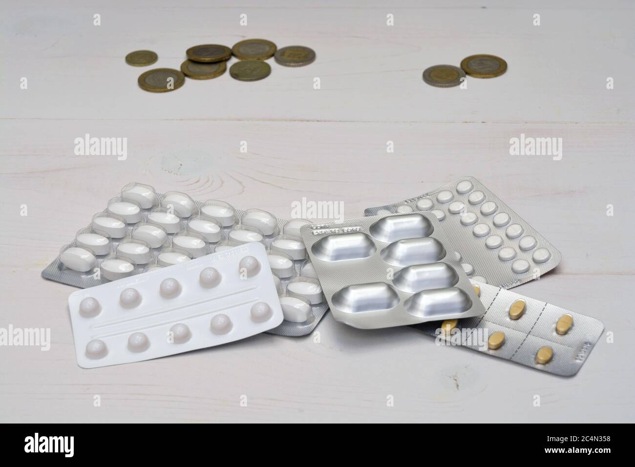 Closeup of tablet packs on a wooden table with coins on the background ...