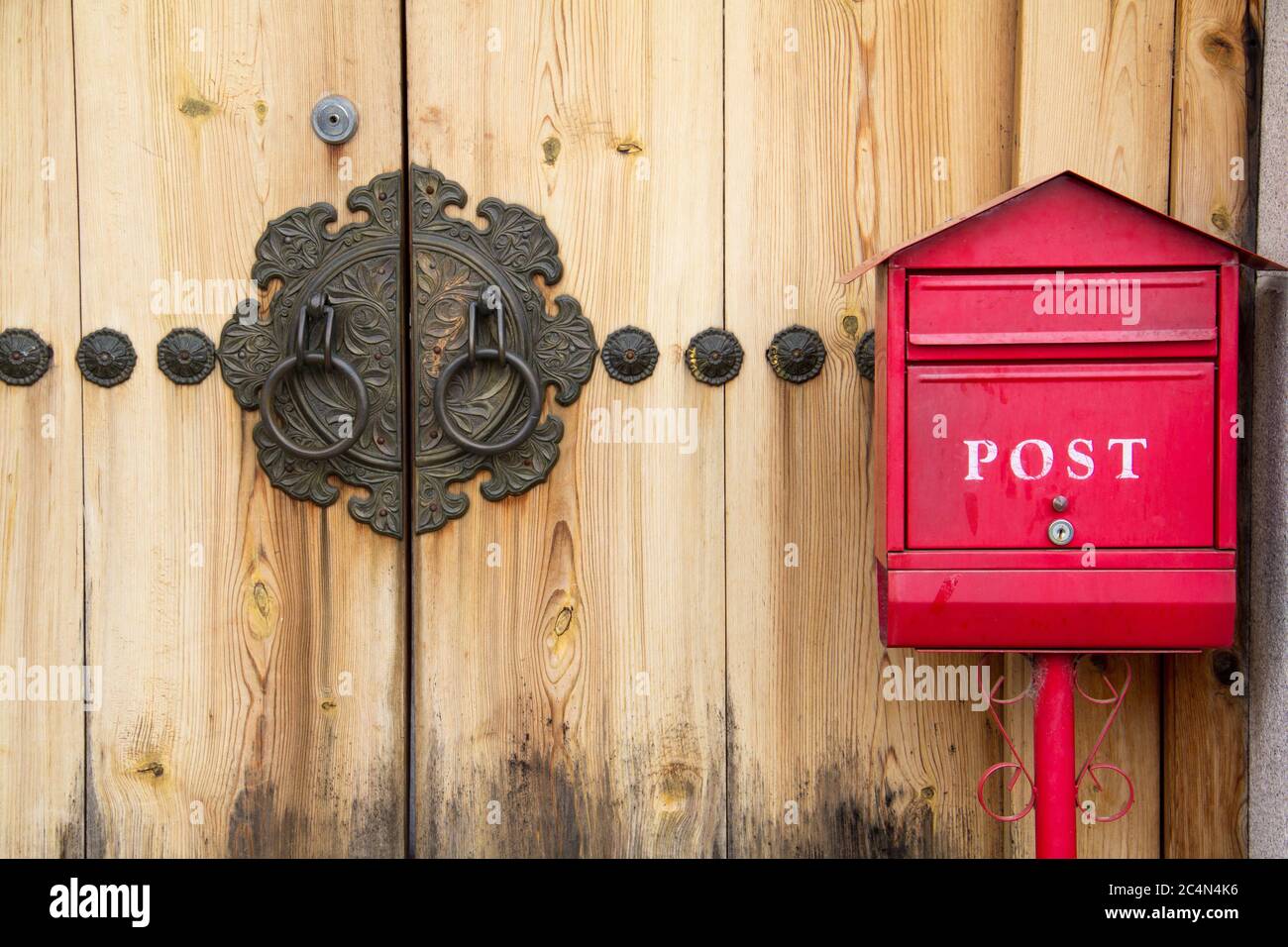 Red mailbox near the wooden gates of a building Stock Photo - Alamy
