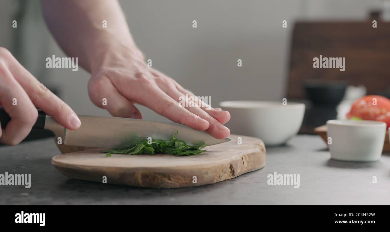 man chopping basil on olive wood board Stock Photo - Alamy