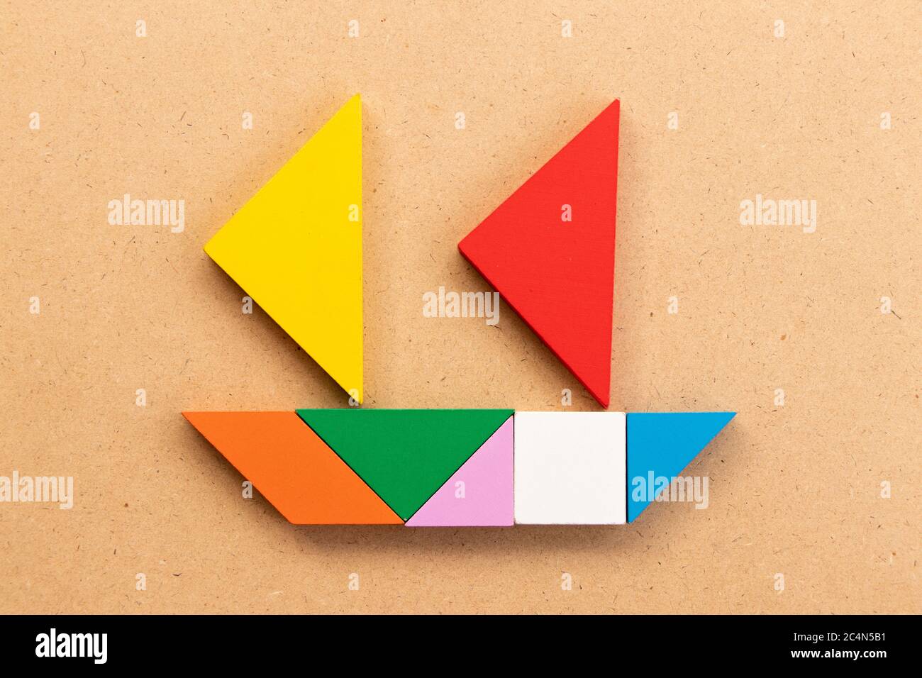 Color tangram puzzle in sailing ship or yacht shape on wood bacground ...