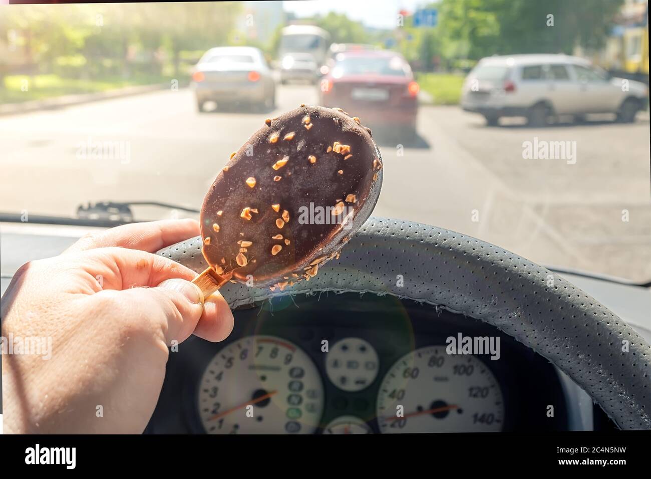 the driver holds the ice cream in his hand while driving the car on the ...