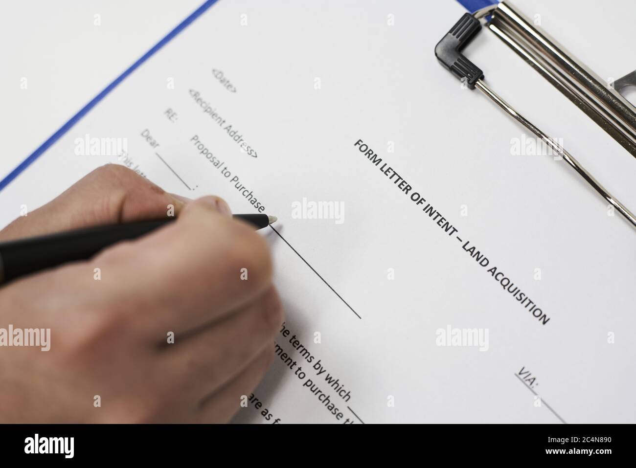 Closeup of a person signing a Form letter of intent for land ...