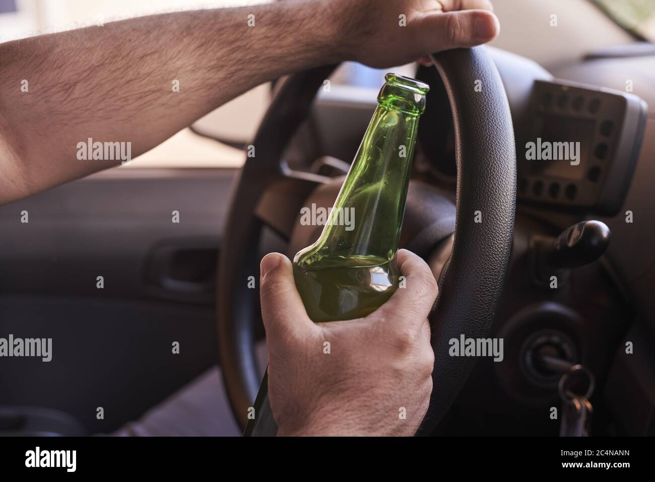 Man driving a car while holding a bottle of beer. Drunk diving, unsafe ...