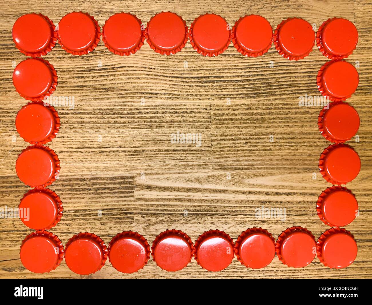 A frame made from red beer bottle tops lids on a rustic wooden table ...