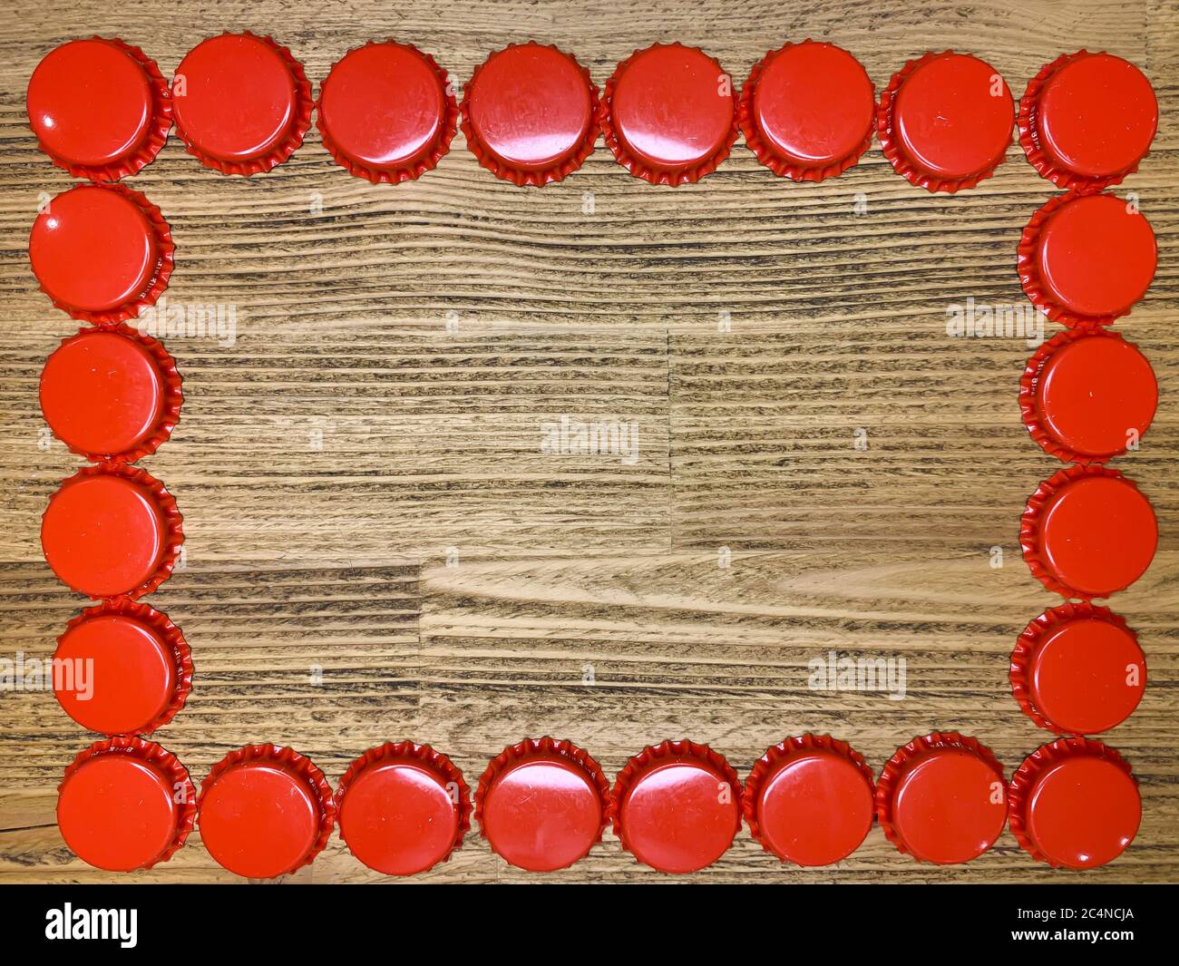 A frame made from red beer bottle tops lids on a rustic wooden table ...