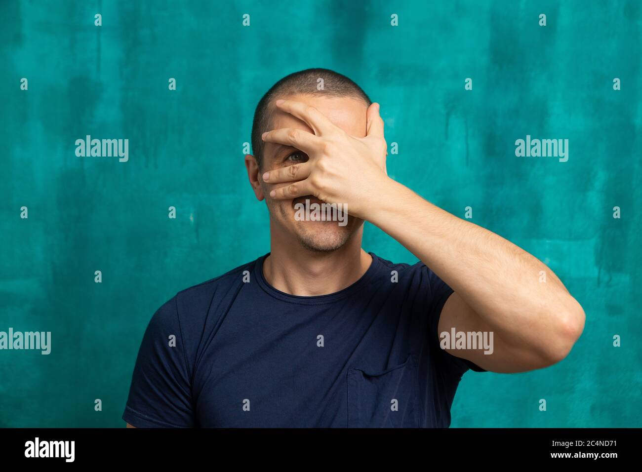 Man closing his face with palm but looking by one eye Stock Photo - Alamy
