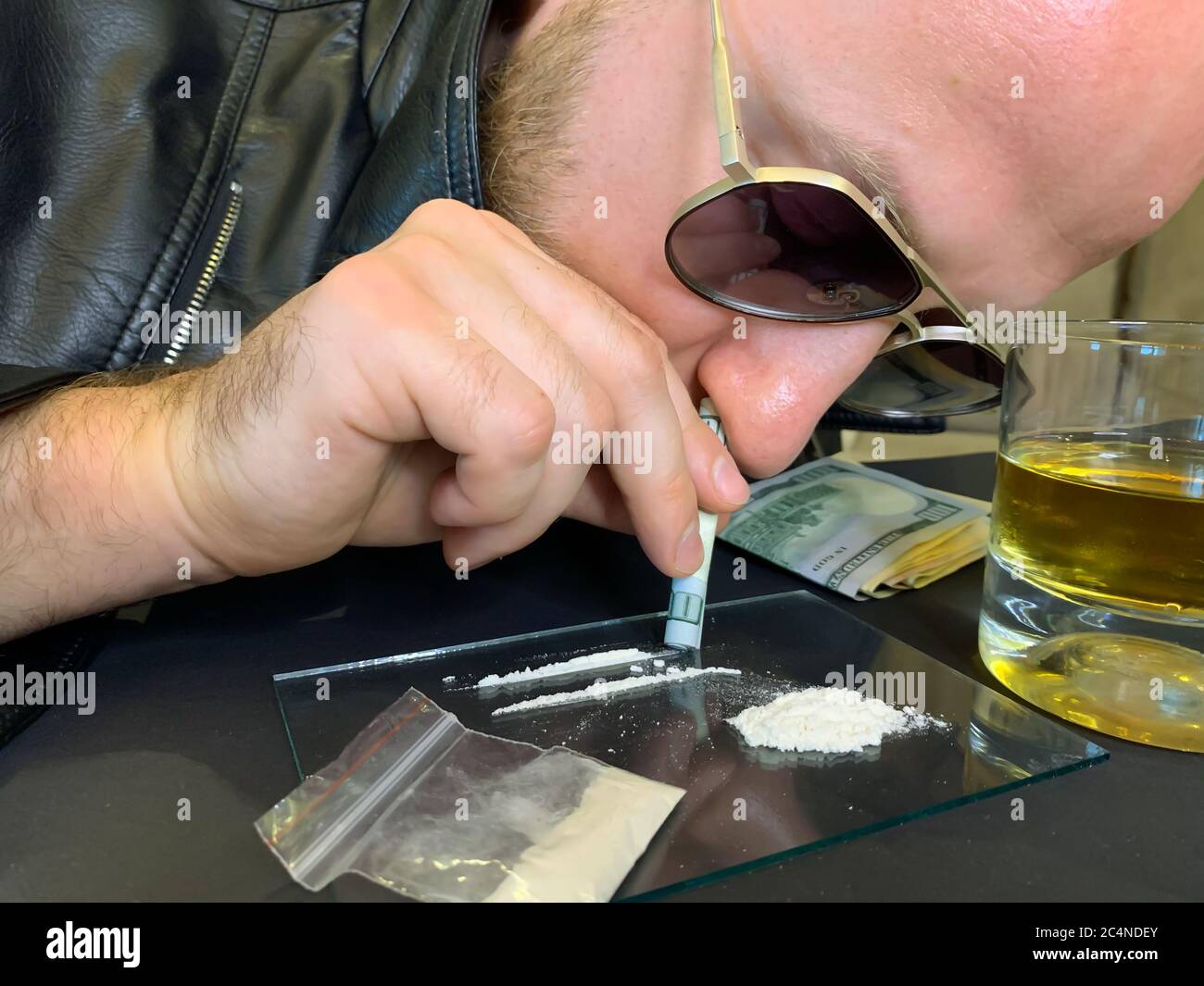Young European man with sun glasses snorting cocaine with rolled 100 ...