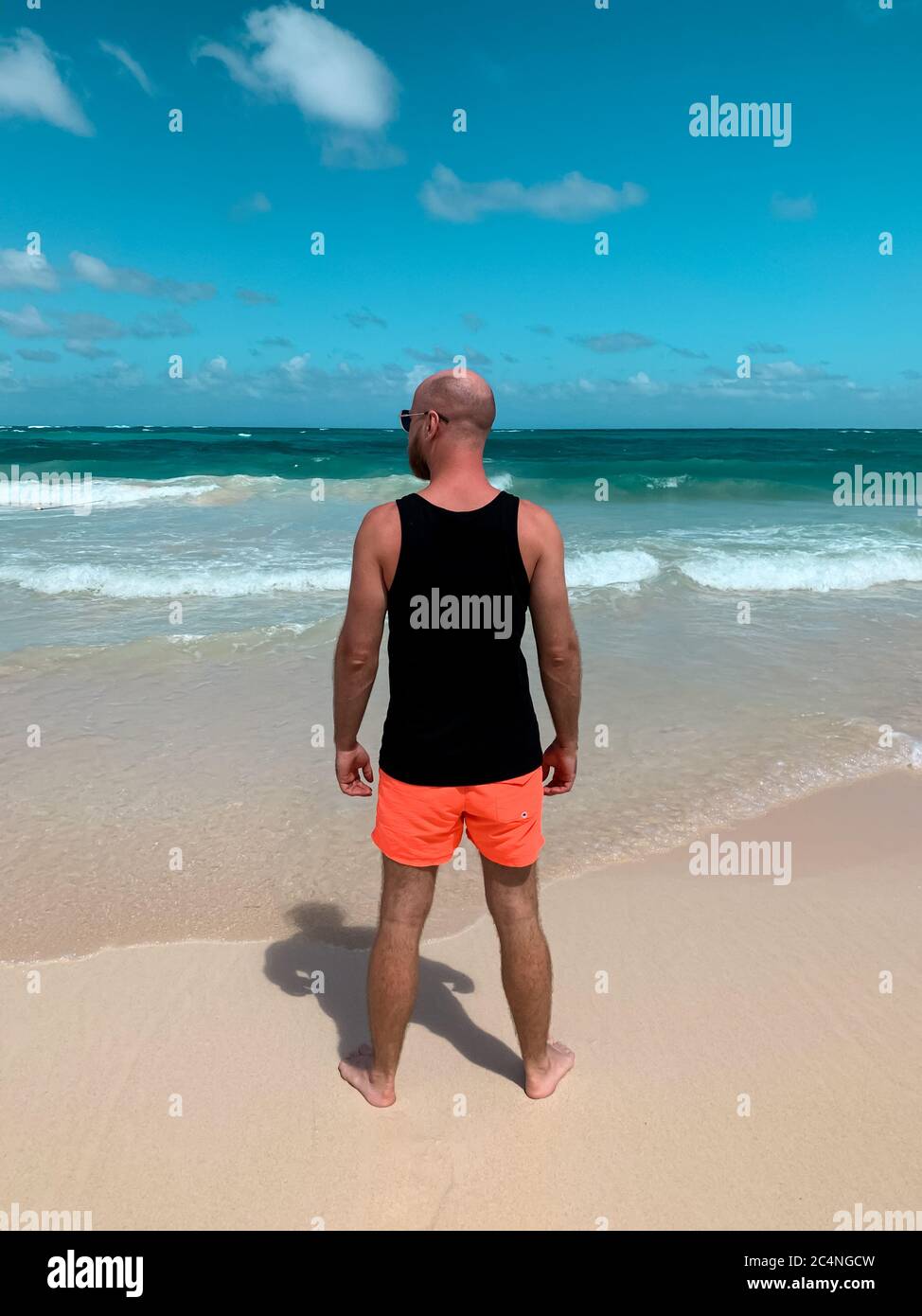 European hairless bearded man male guy standing on the beach in black sleeveless shirt singlet ...