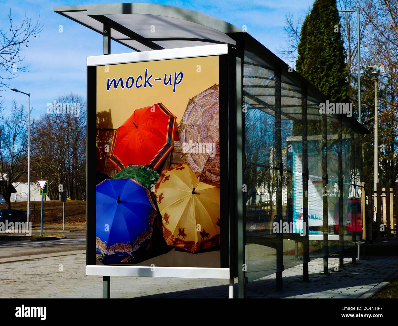 glass bus shelter at bus stop. mock-up background. green lawn and trees ...