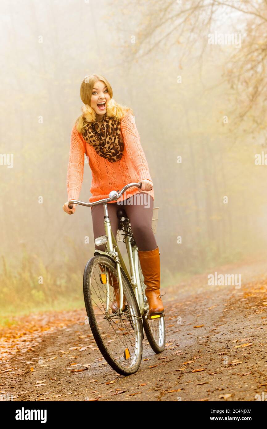 Happy active woman riding bike bicycle in foggy fall autumn park. Glad ...