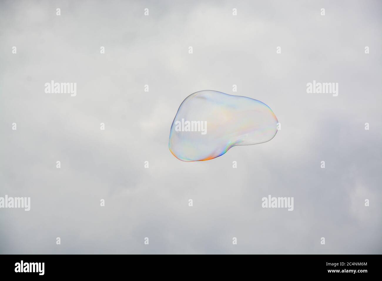 Isolated shot of a deformed soap bubble floating in the air in front of ...