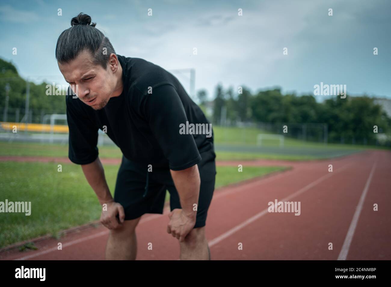 exhausted athlete resting on track after running or workout exercising ...