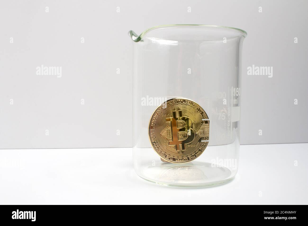 Closeup of a BTC bitcoin coin in a laboratory beaker, ready for an ...