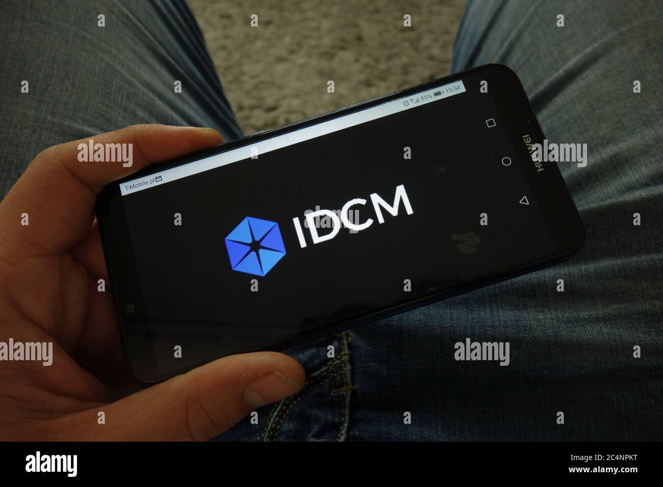 Man holding smartphone with IDCM cryptocurrency exchange logo Stock ...