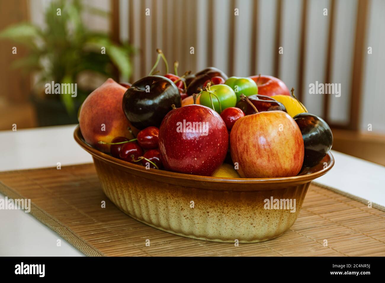 a bowl of mixed fresh fruits, apples, peaches, green and red plums ...