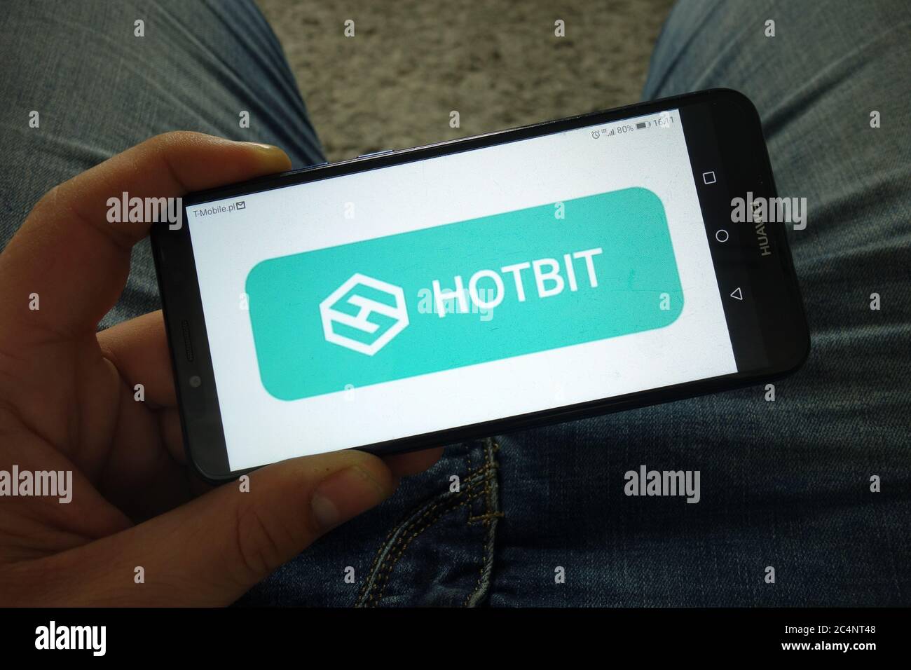 Man holding smartphone with Hotbit cryptocurrency exchange logo Stock ...