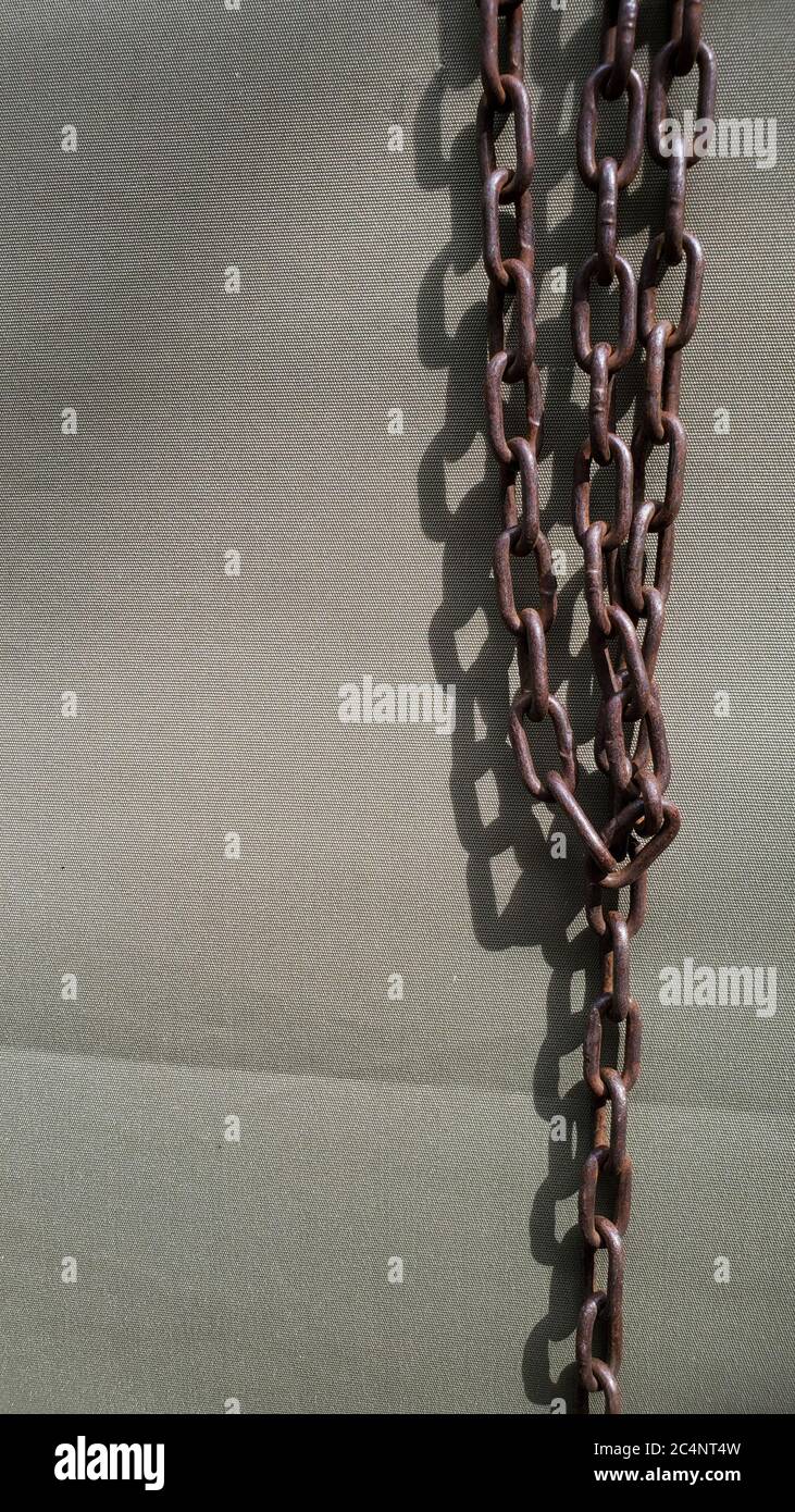 Closeup of old rusty metal chains on rough fabric background in bright ...